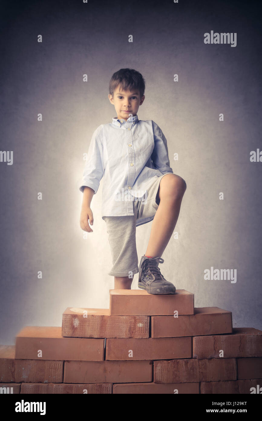 Boy stepping on bricks Stock Photo - Alamy