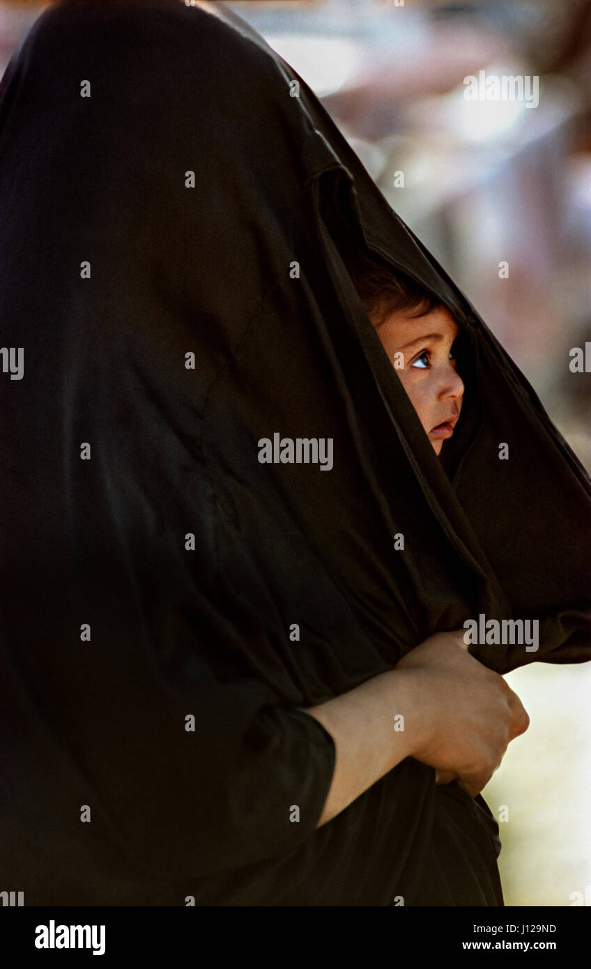 A Iraqi refugee mother shields her son from the sun as she waits for ...
