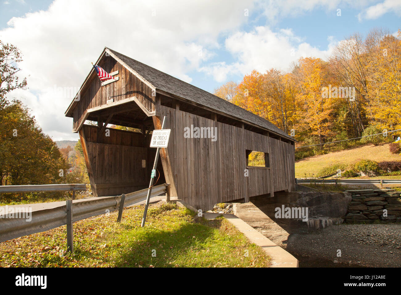 Antique covered wooden bridge with an American flag in Vermont ...