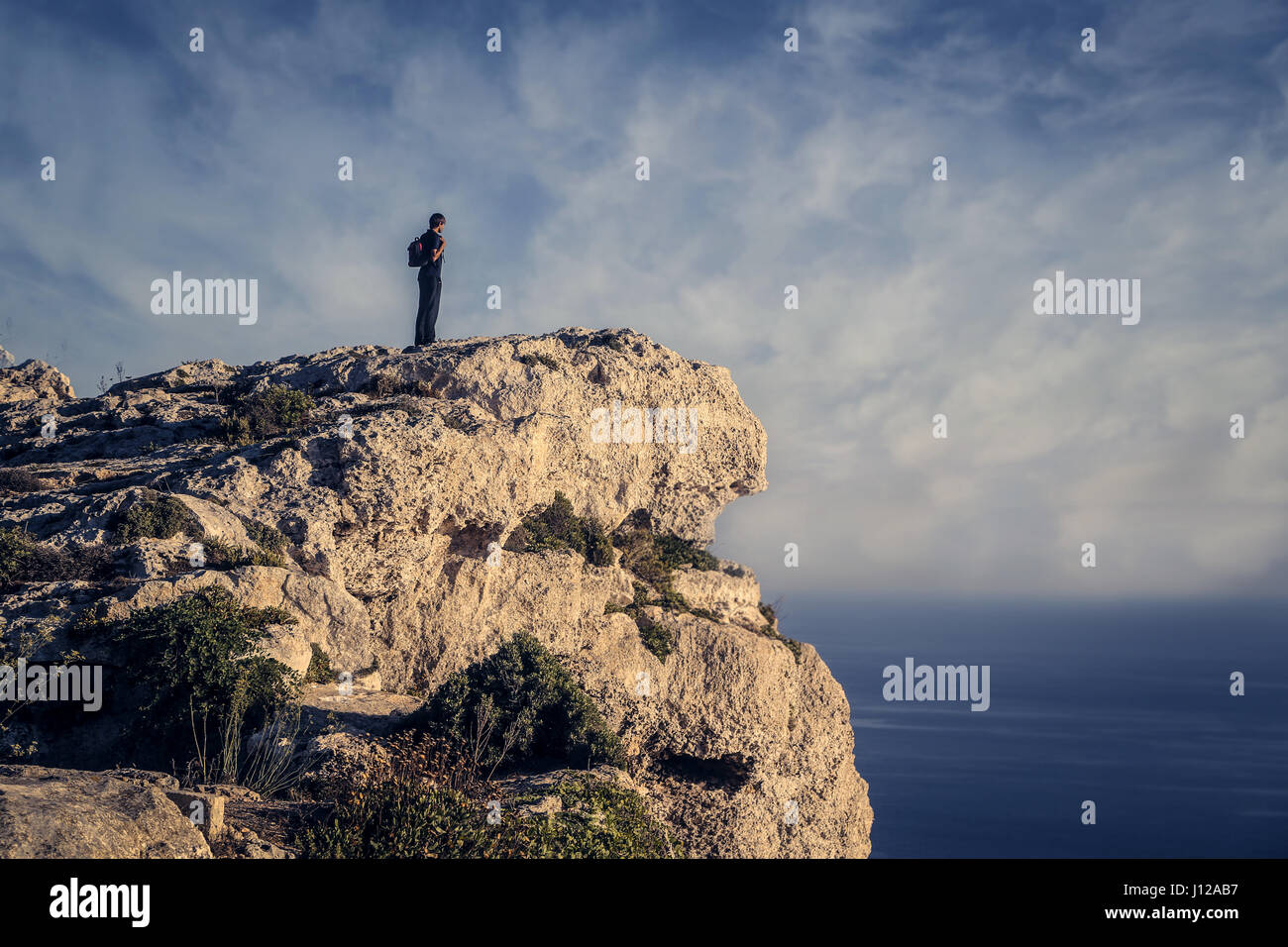 Man standing on cliff Stock Photo - Alamy