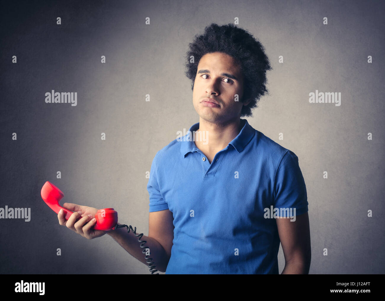 Sad man holding red retro phone Stock Photo - Alamy