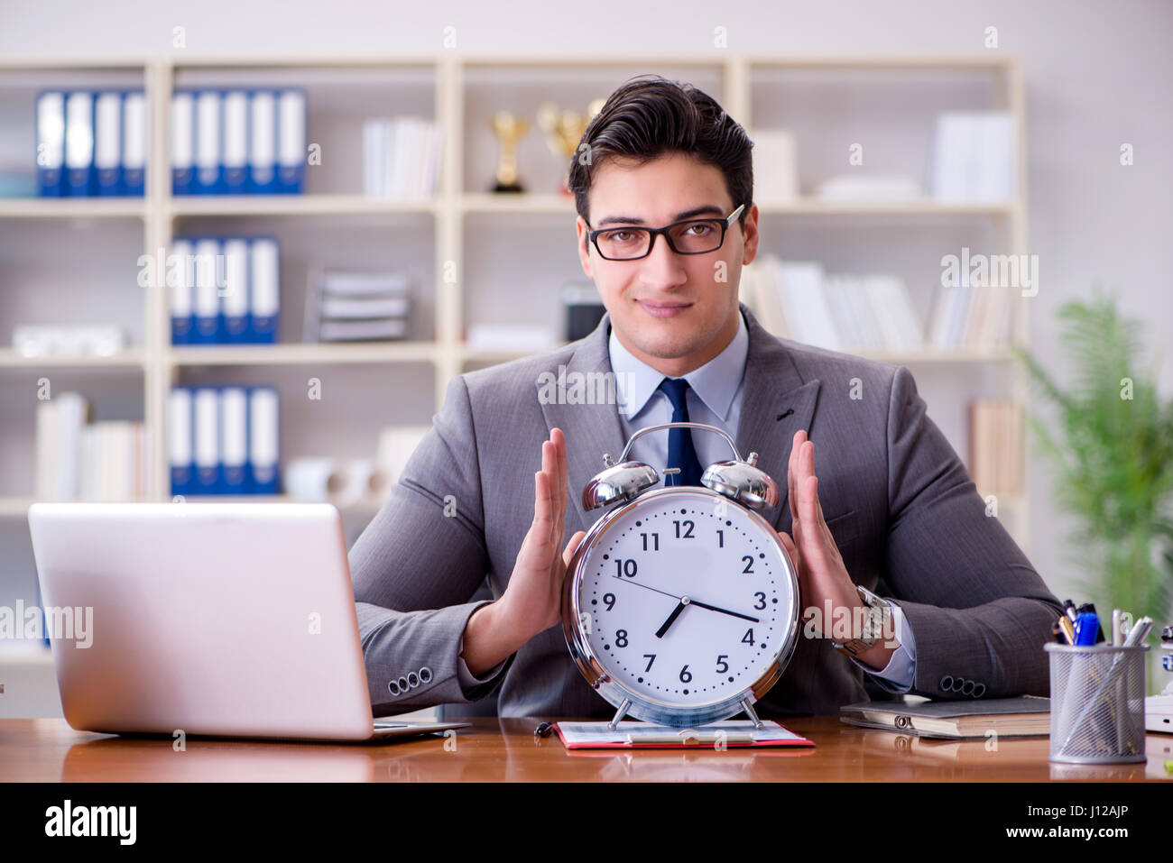 Young businessman in time management concept Stock Photo - Alamy