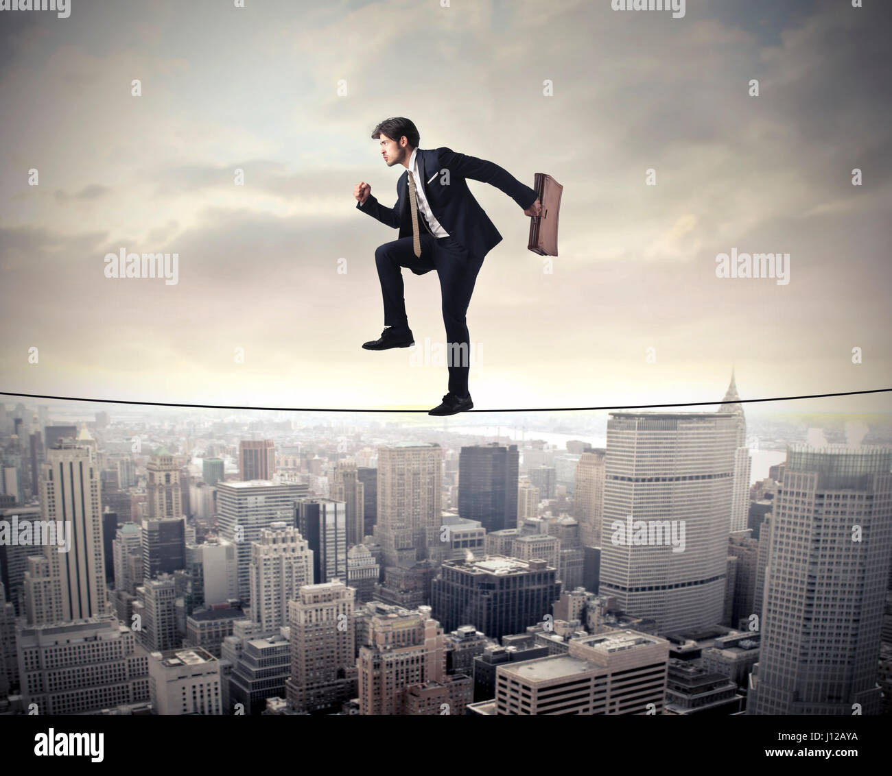 Businessman walking on tight rope Stock Photo - Alamy