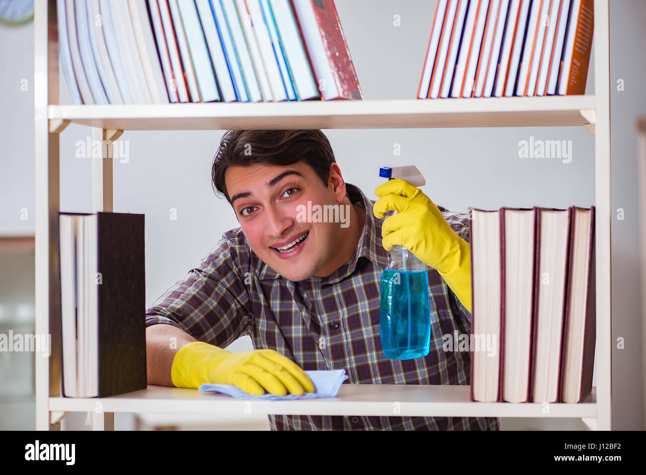 Man cleaning dust from bookshelf Stock Photo - Alamy