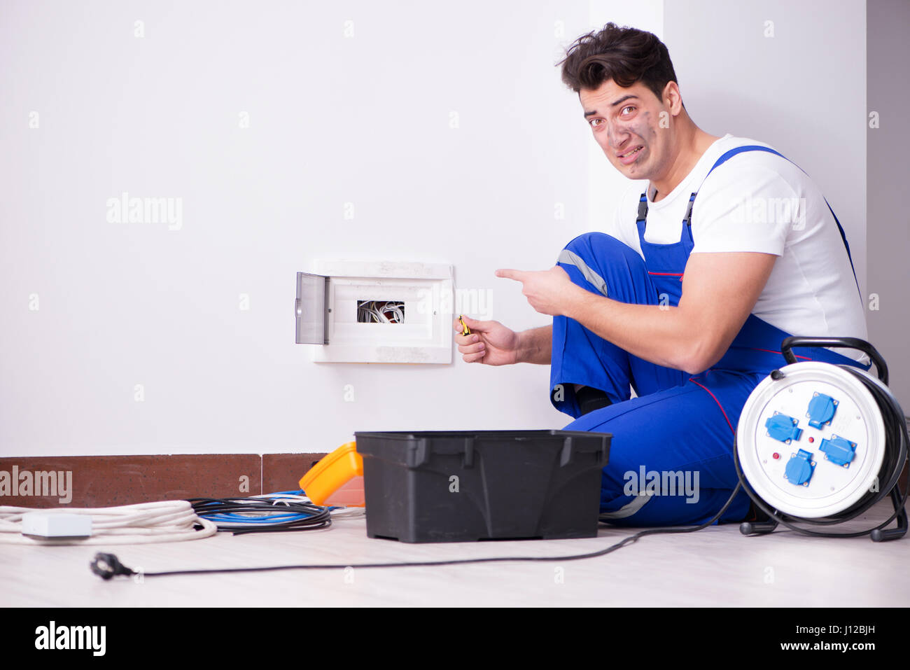 Funny young electrician working on socket at home Stock Photo - Alamy