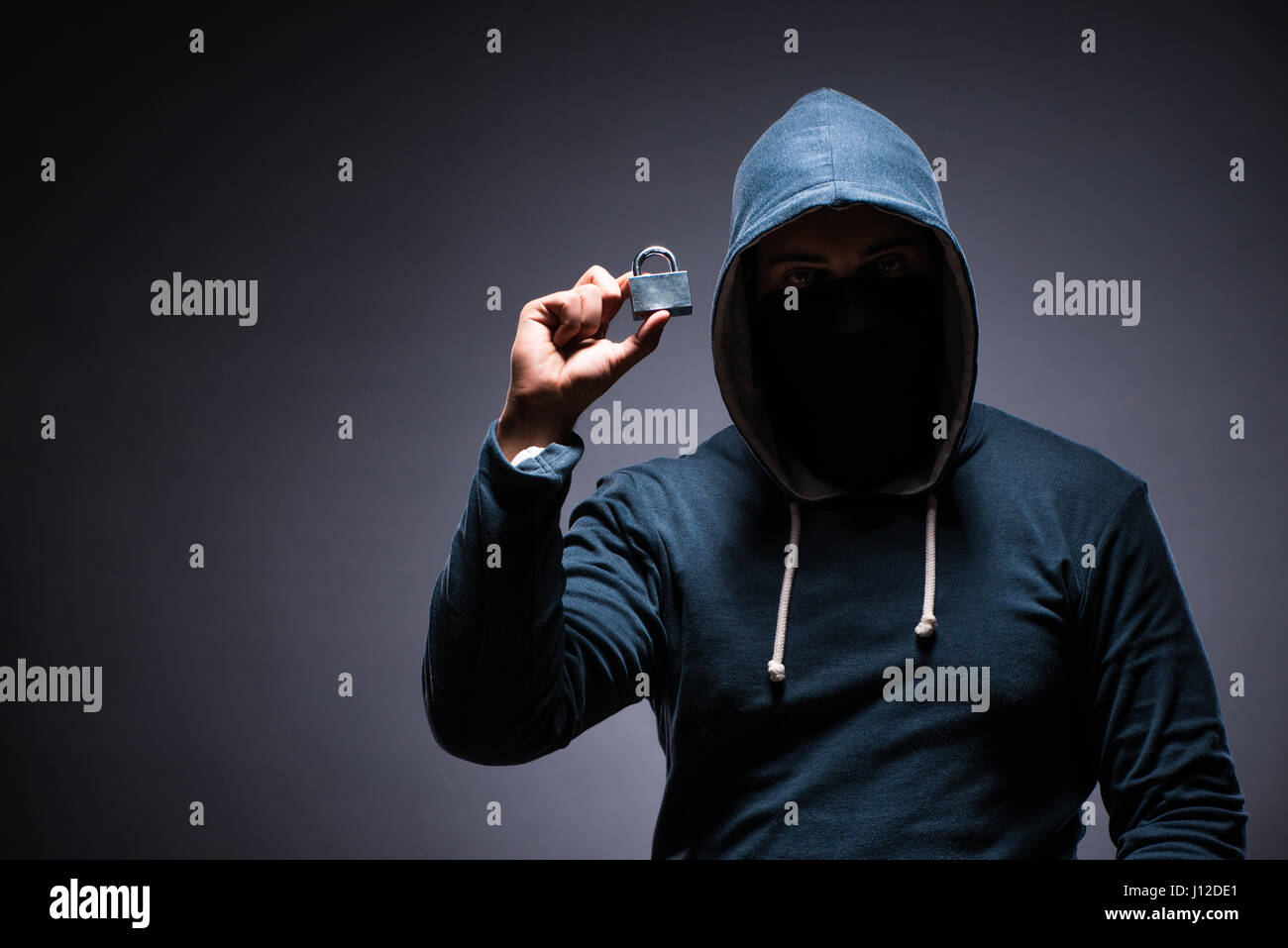 Hacker wearing hood in dark room Stock Photo - Alamy