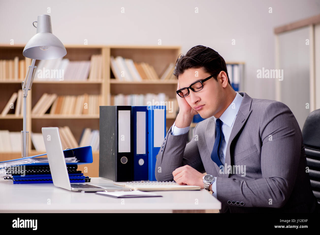 Sleepy businessman working in office Stock Photo - Alamy