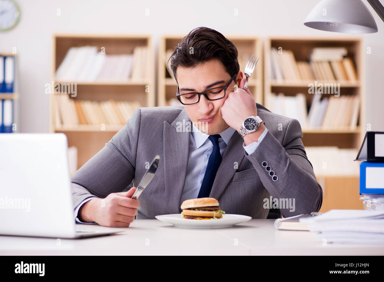 Hungry funny businessman eating junk food sandwich Stock Photo - Alamy