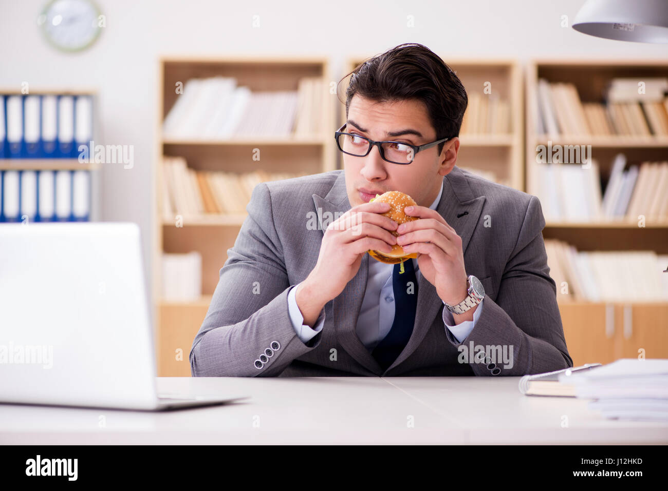 Hungry funny businessman eating junk food sandwich Stock Photo - Alamy