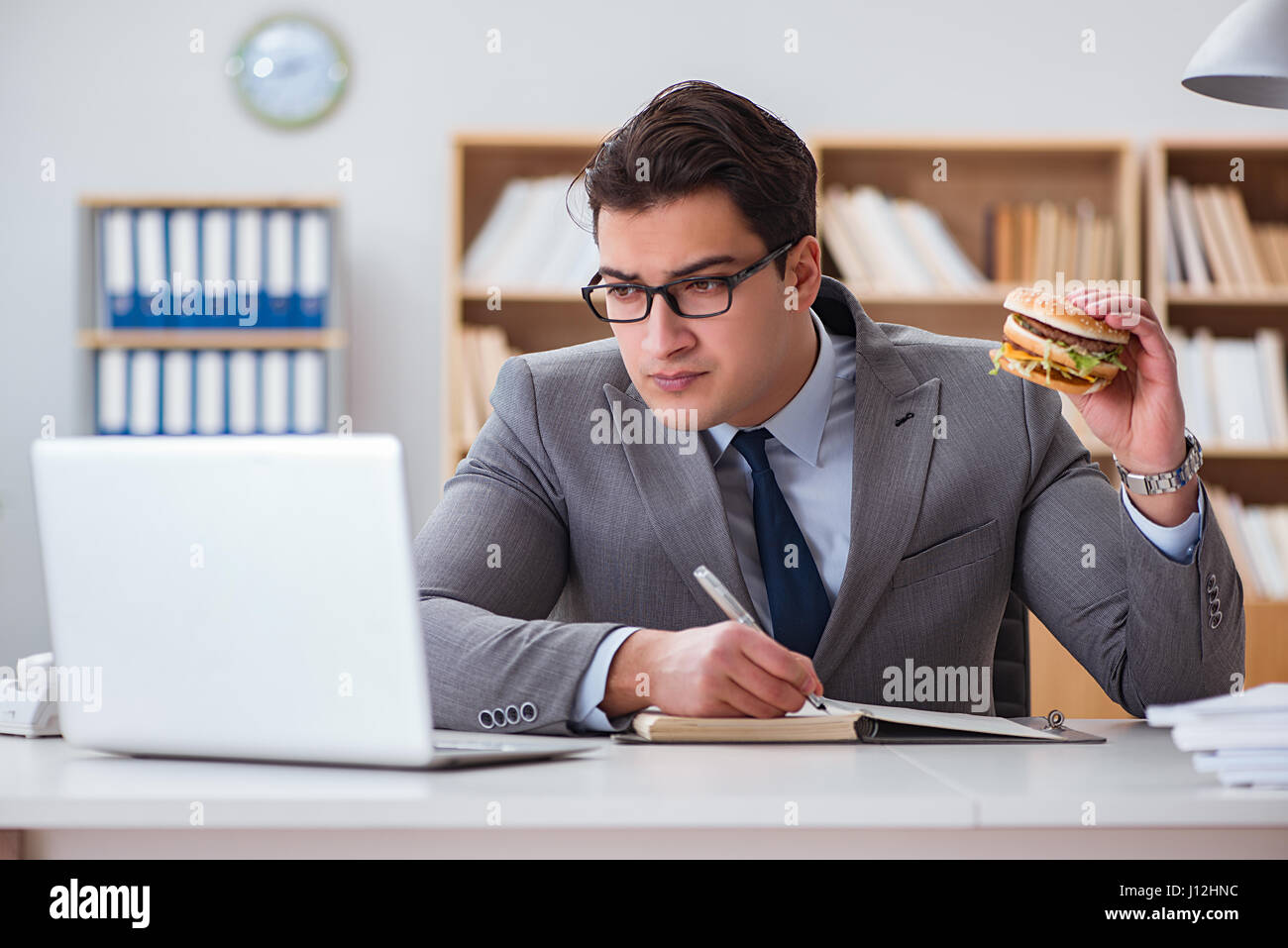 Hungry funny businessman eating junk food sandwich Stock Photo - Alamy