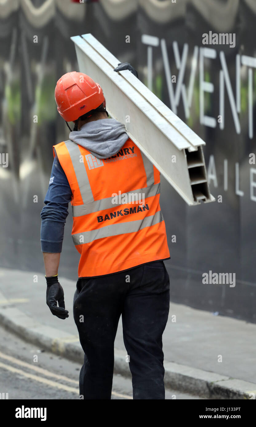 Men carrying steel girders rsj steels workmen on a building site near ...