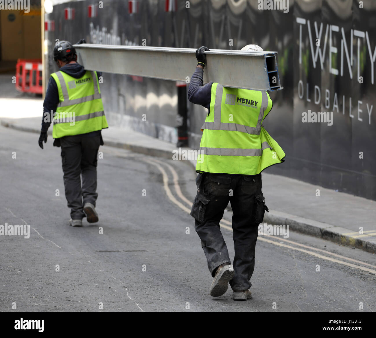 Men carrying steel girders rsj steels workmen on a building site near ...