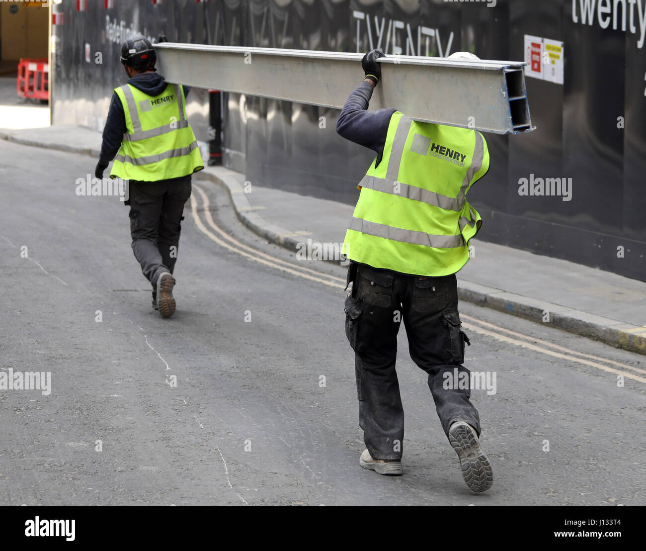 Men carrying steel girders rsj steels workmen on a building site near ...