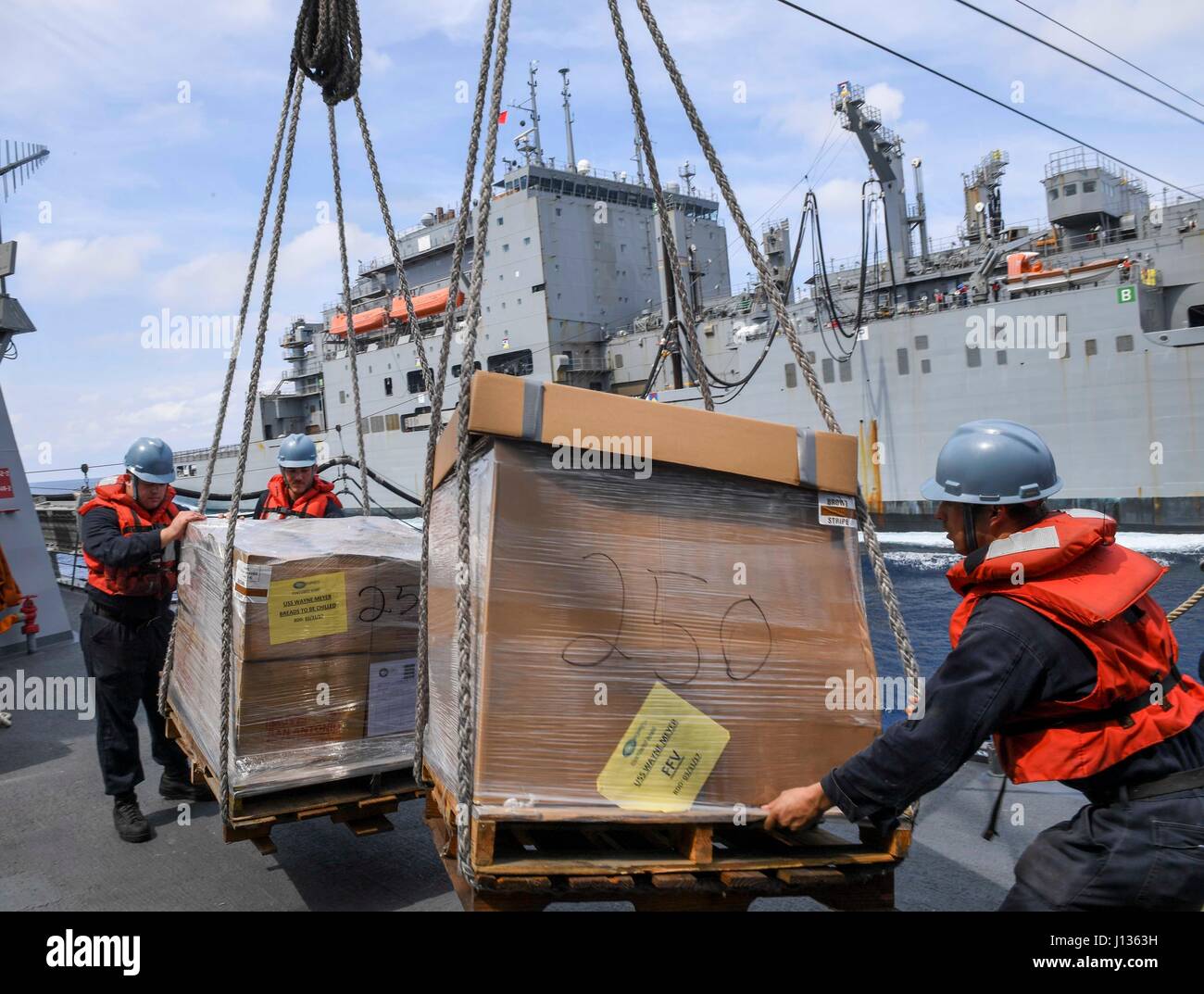 Sailors aboard USS Wayne E. Meyer transfer cargo from USNS Cesar Chavez ...