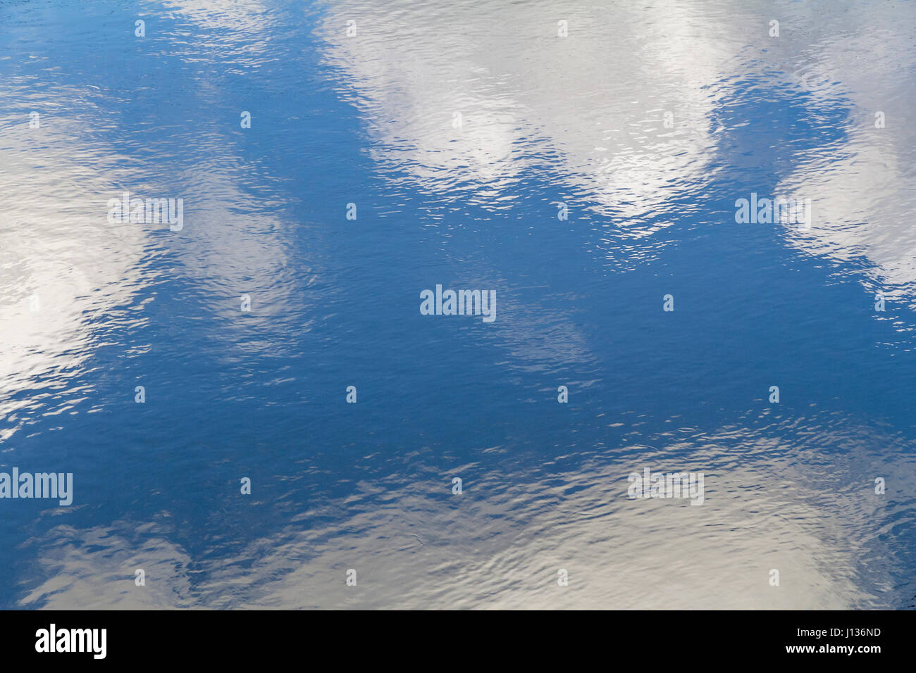 full frame water surface mirroring a clouded blue sky Stock Photo - Alamy