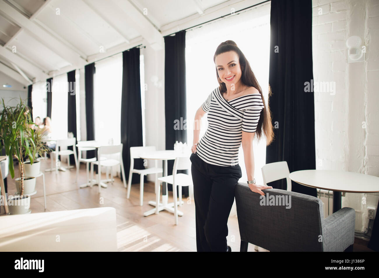 Smiling businesswoman leaning against a chair and smiling while looking ...