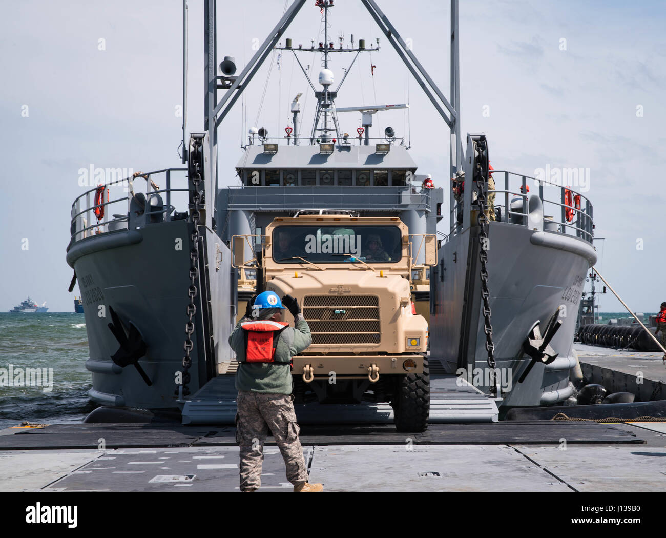 Sailors from Assault Craft Unit 1 load a medium tactical vehicle onto ...