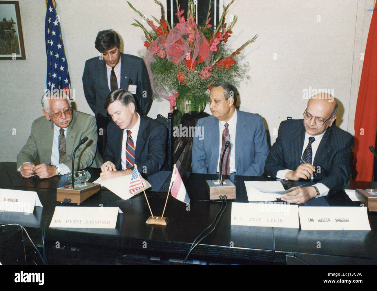 THERE ARE A GROUP OF MEN SITTING AT THE TABLE LOOKING AND SIGNING SOME ...