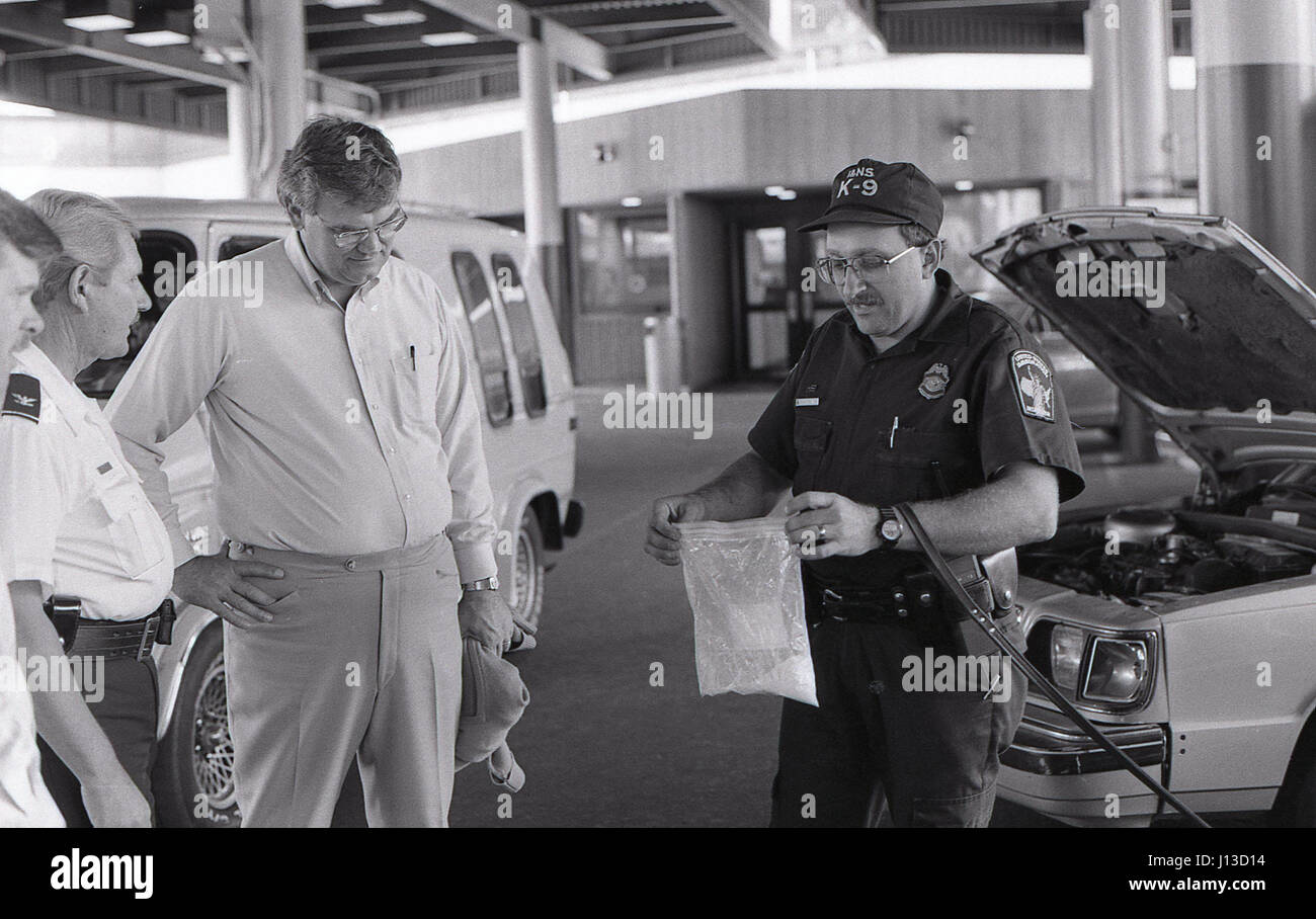 Military officer and K9 conduct a vehicle inspection as part of ...