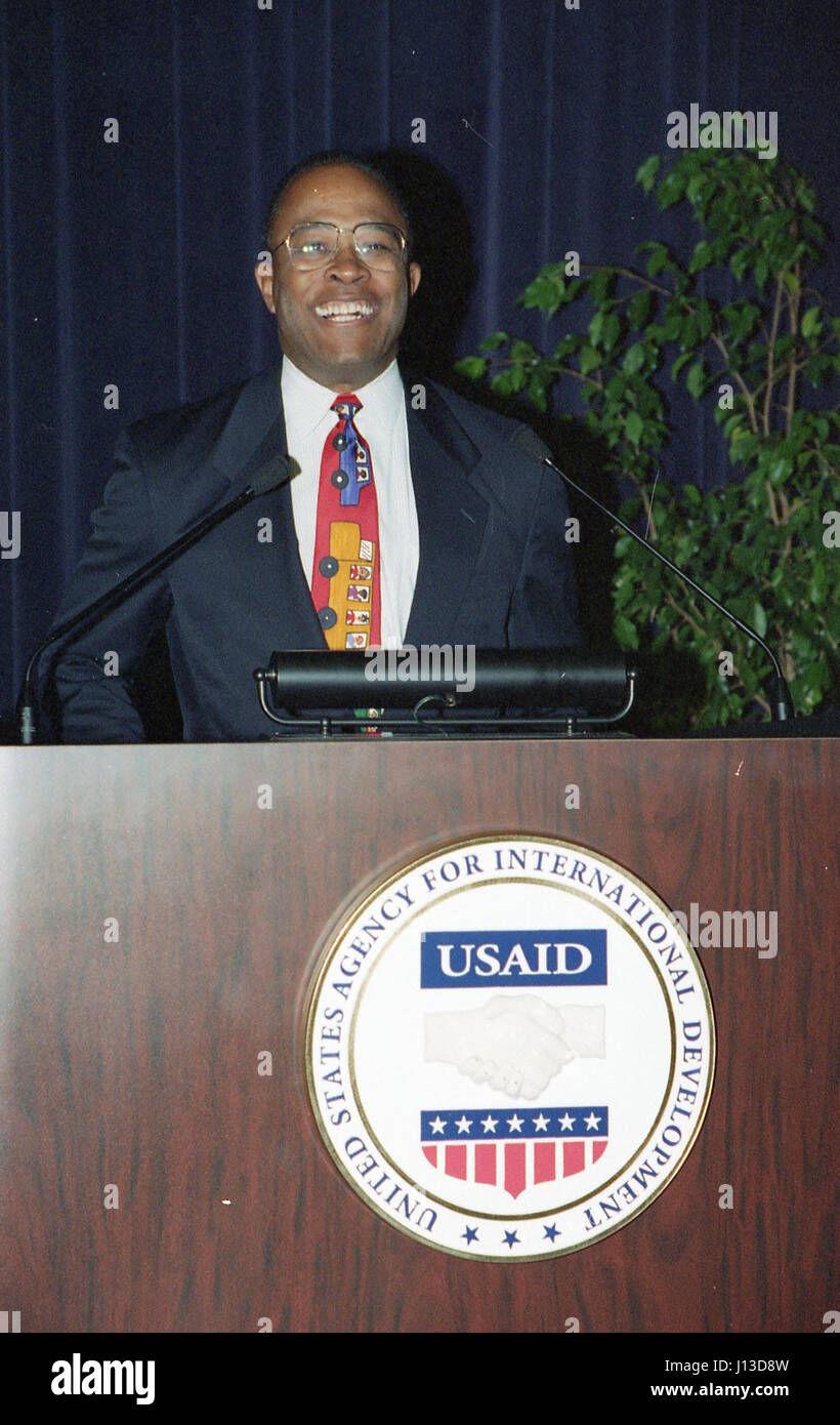 A man accepts an award while delivering remarks at a podium during a ...