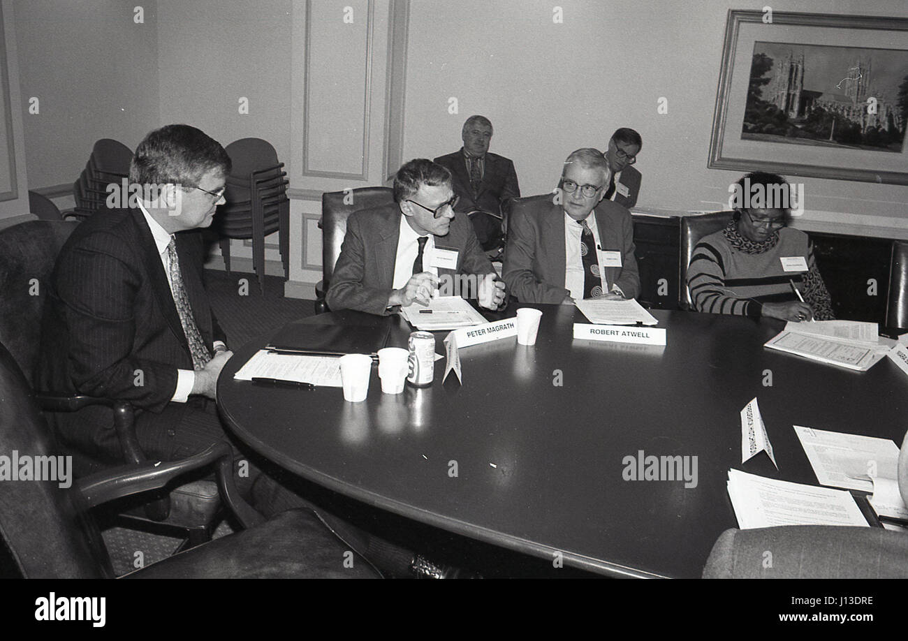 A group of men and women engage in conversation in a professional ...