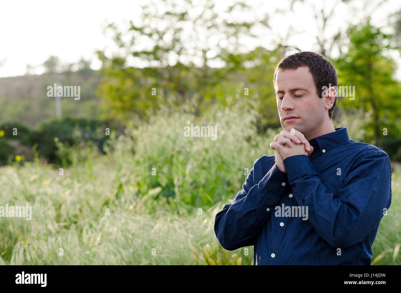 Man praying outdoors with his hands folded together Stock Photo - Alamy