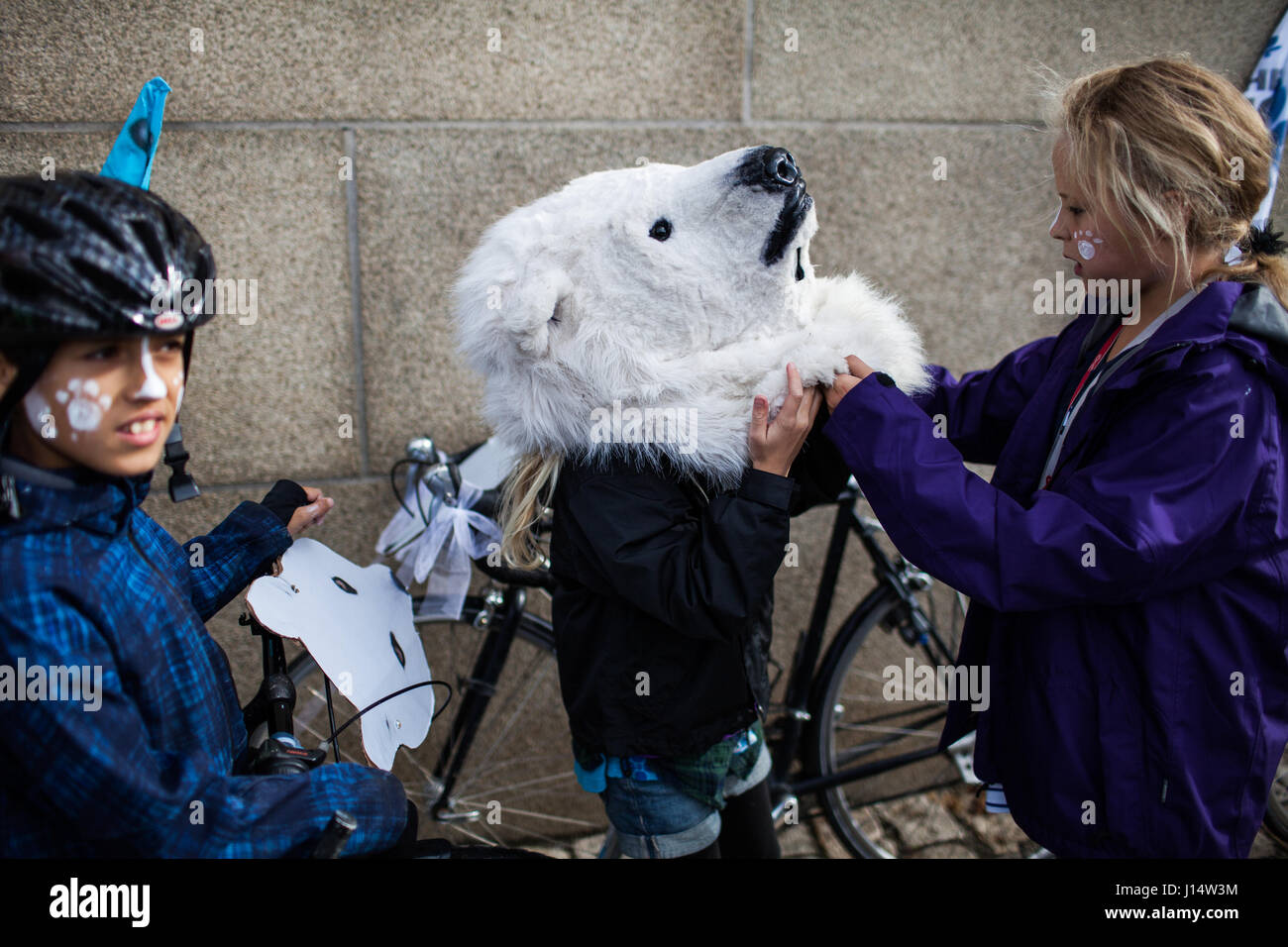 A young climate activist is trying the head of a polar bear costume at ...