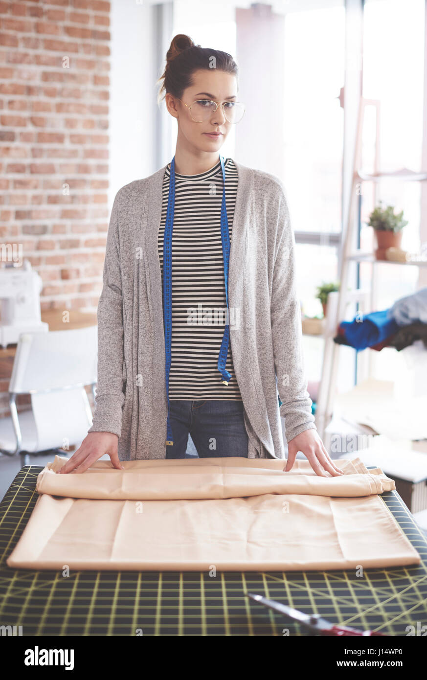 Female dressmaker measuring textile material Stock Photo - Alamy