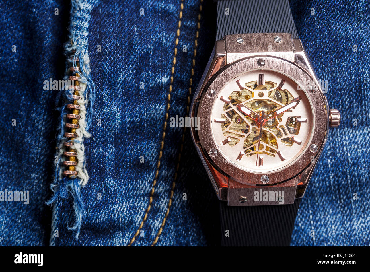 Automatic men watch with visible mechanism on blue jeans background ...