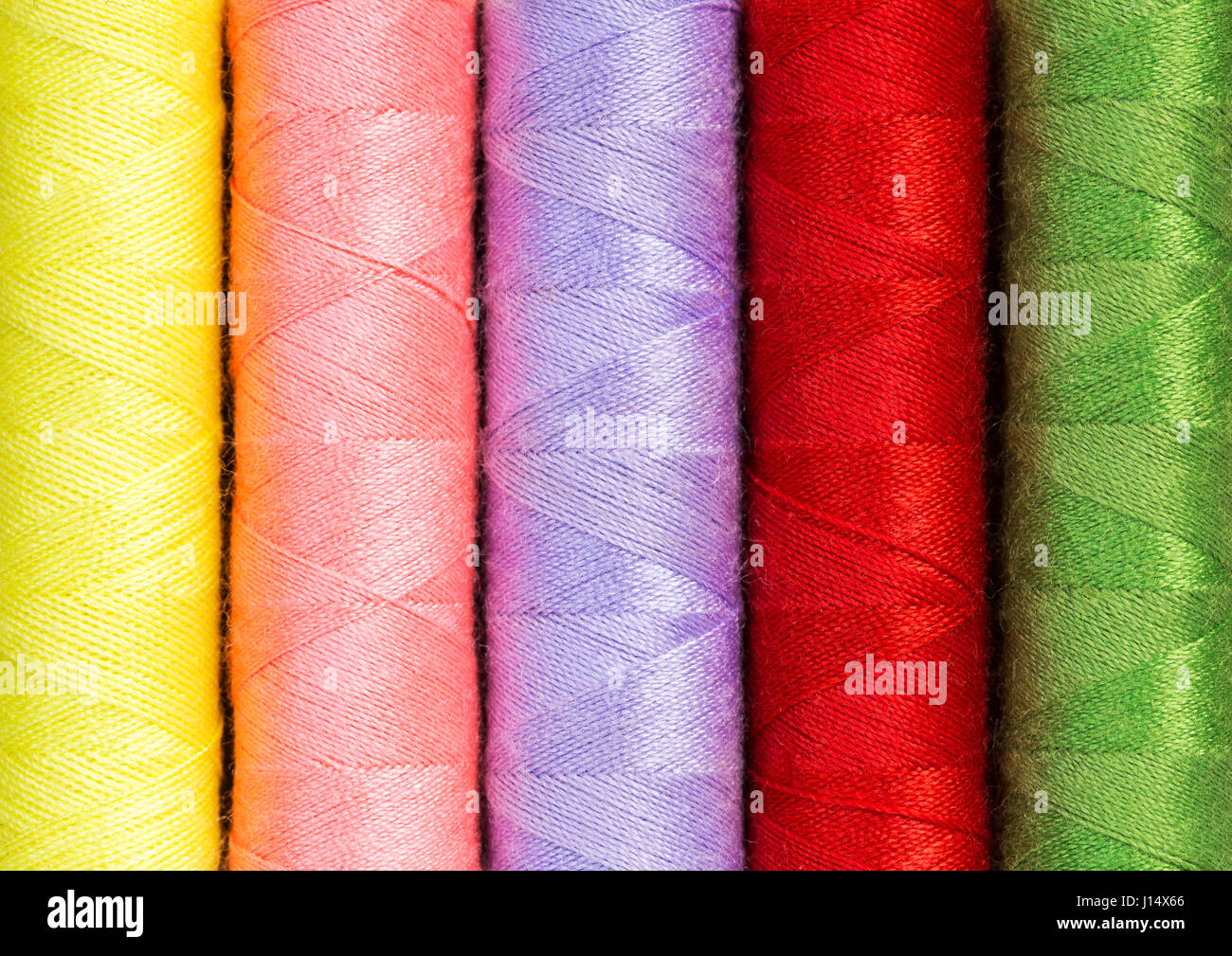 Close up colorful thread spools used in fabric and textile industry ...