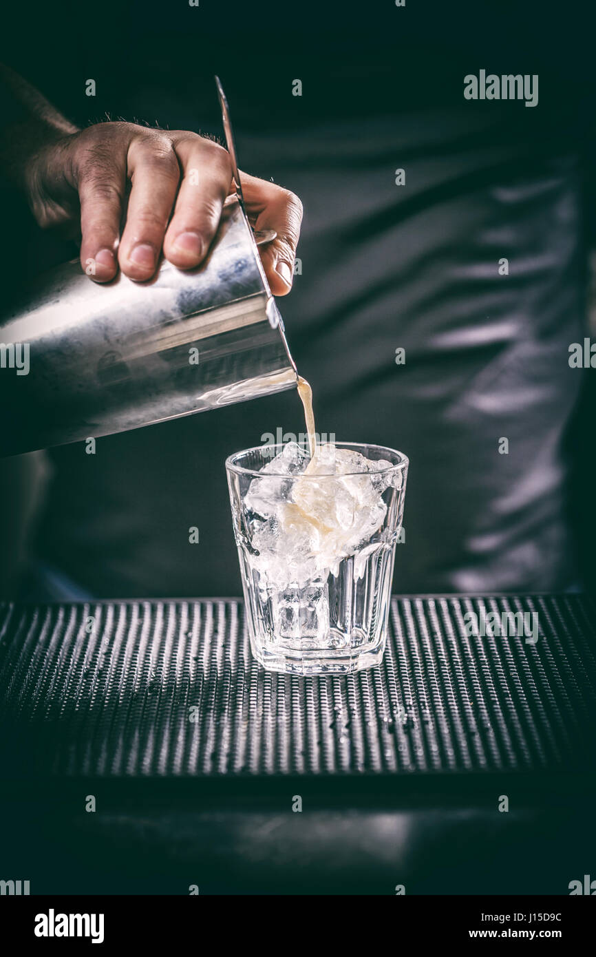 Barman hand with shake mixer pouring cocktail into glass Stock Photo ...