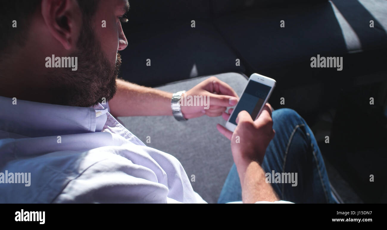 relaxed young businessman using smart phone at modern startup business ...