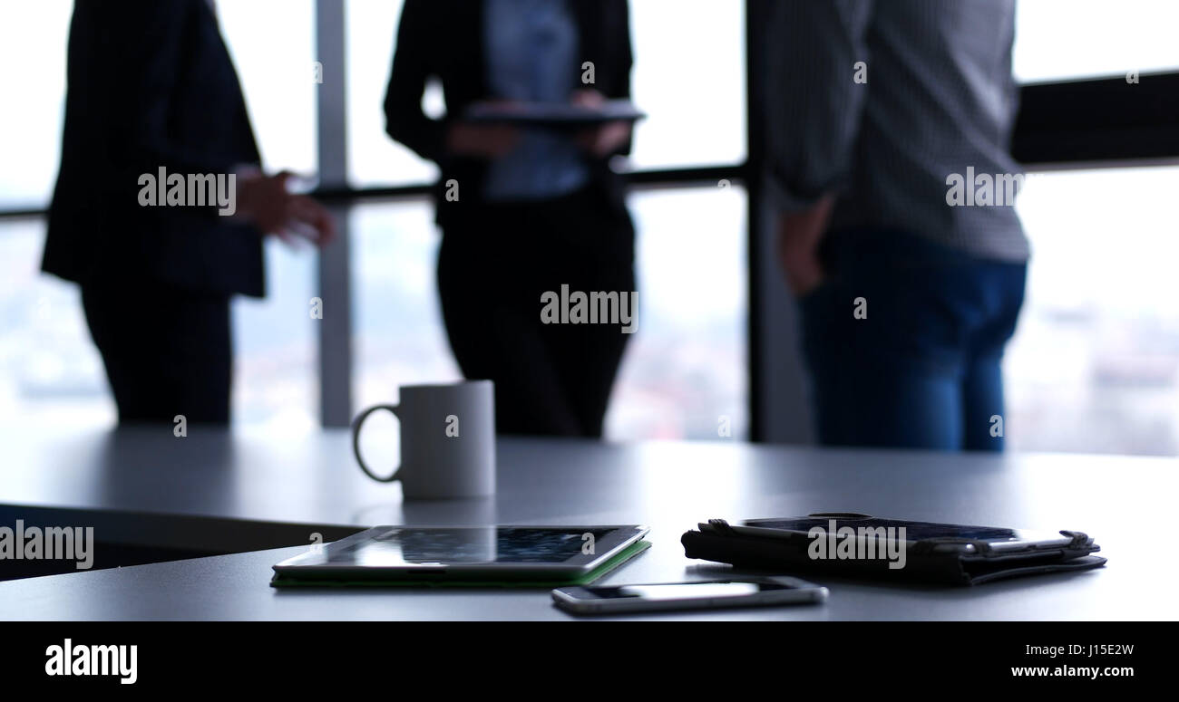 Devices on table with business people in background in modern office ...