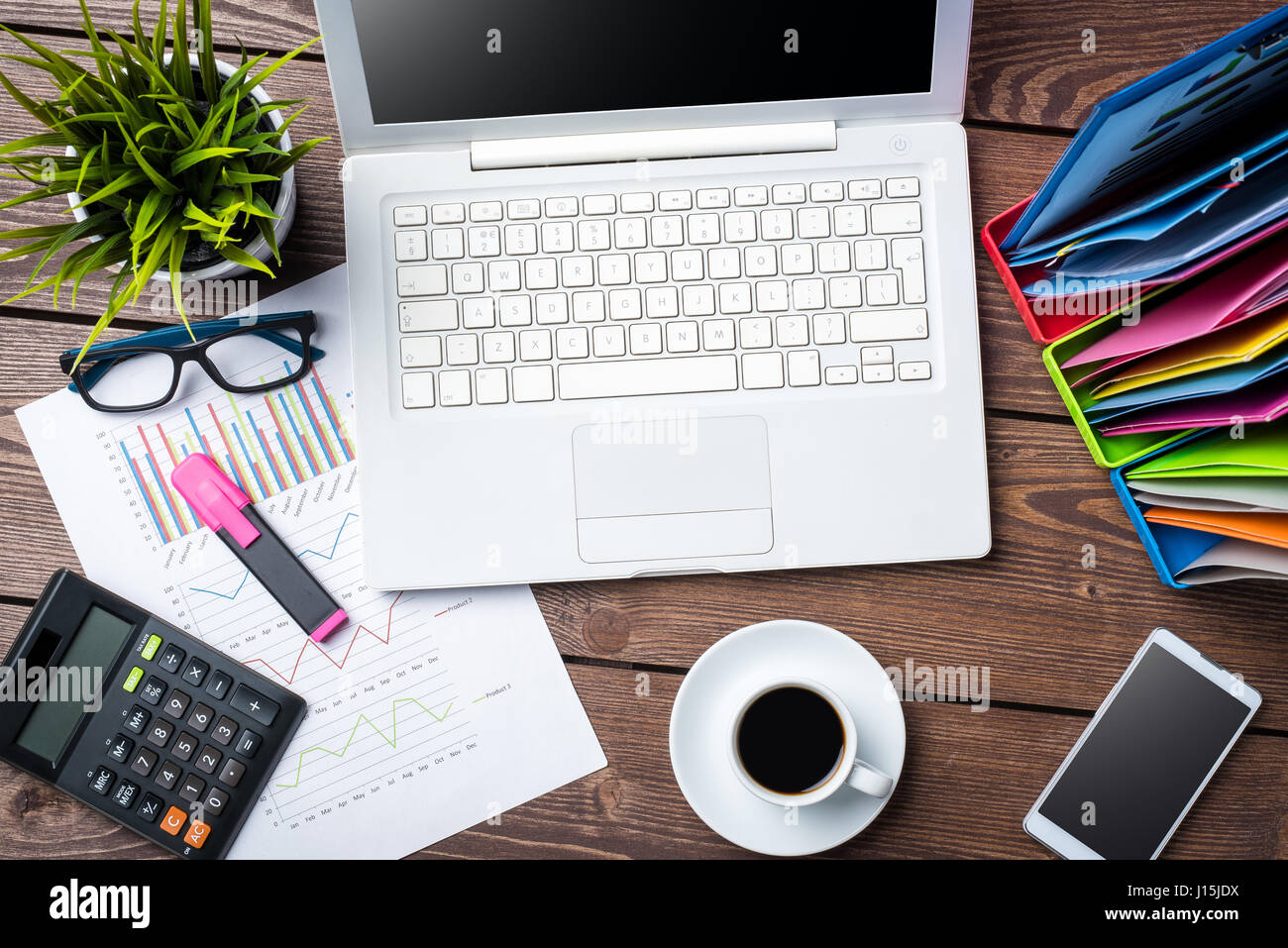 Overhead shot of office desktop with modern computer, graphs and charts ...