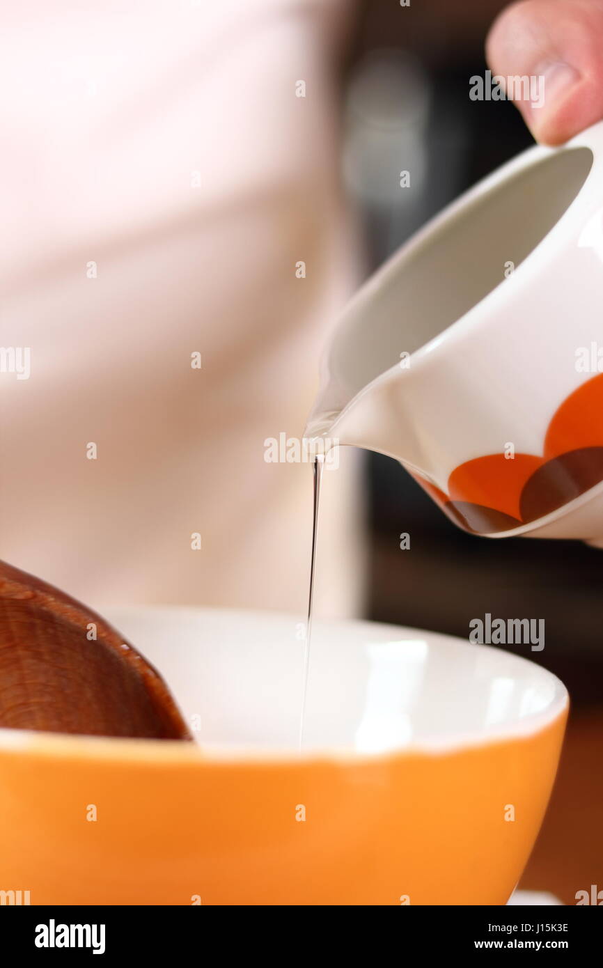 Pouring oil to an egg yolk. Making mayonnaise with a wooden spoon Stock ...