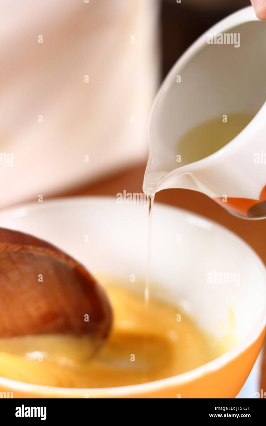 Pouring oil to an egg yolk. Making mayonnaise with a wooden spoon Stock ...