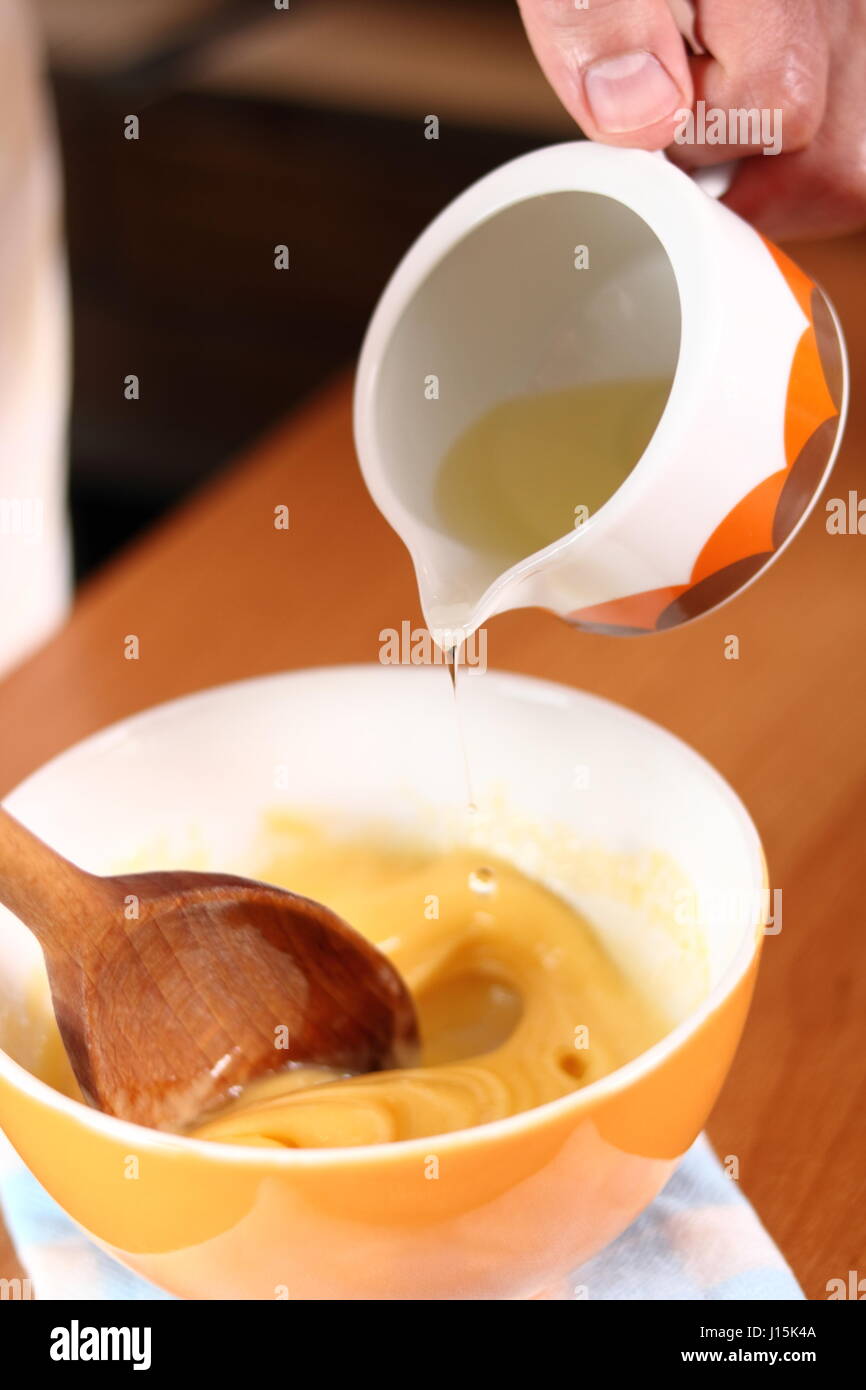 Pouring oil to an egg yolk. Making mayonnaise with a wooden spoon Stock ...