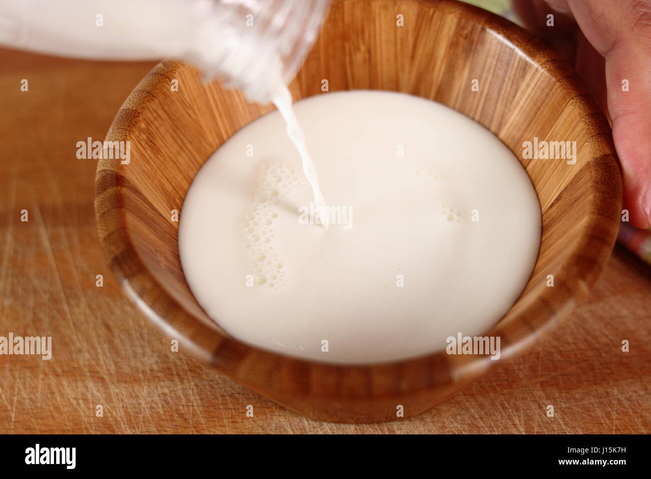 Pouring milk into wooden bowl Stock Photo - Alamy