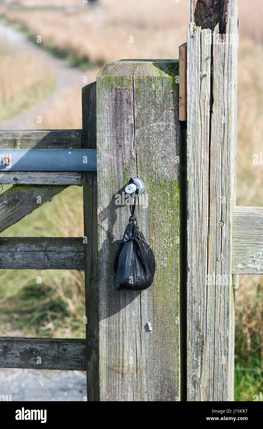 A bag of dog poop left on a gate along a footpath by a careless dog ...
