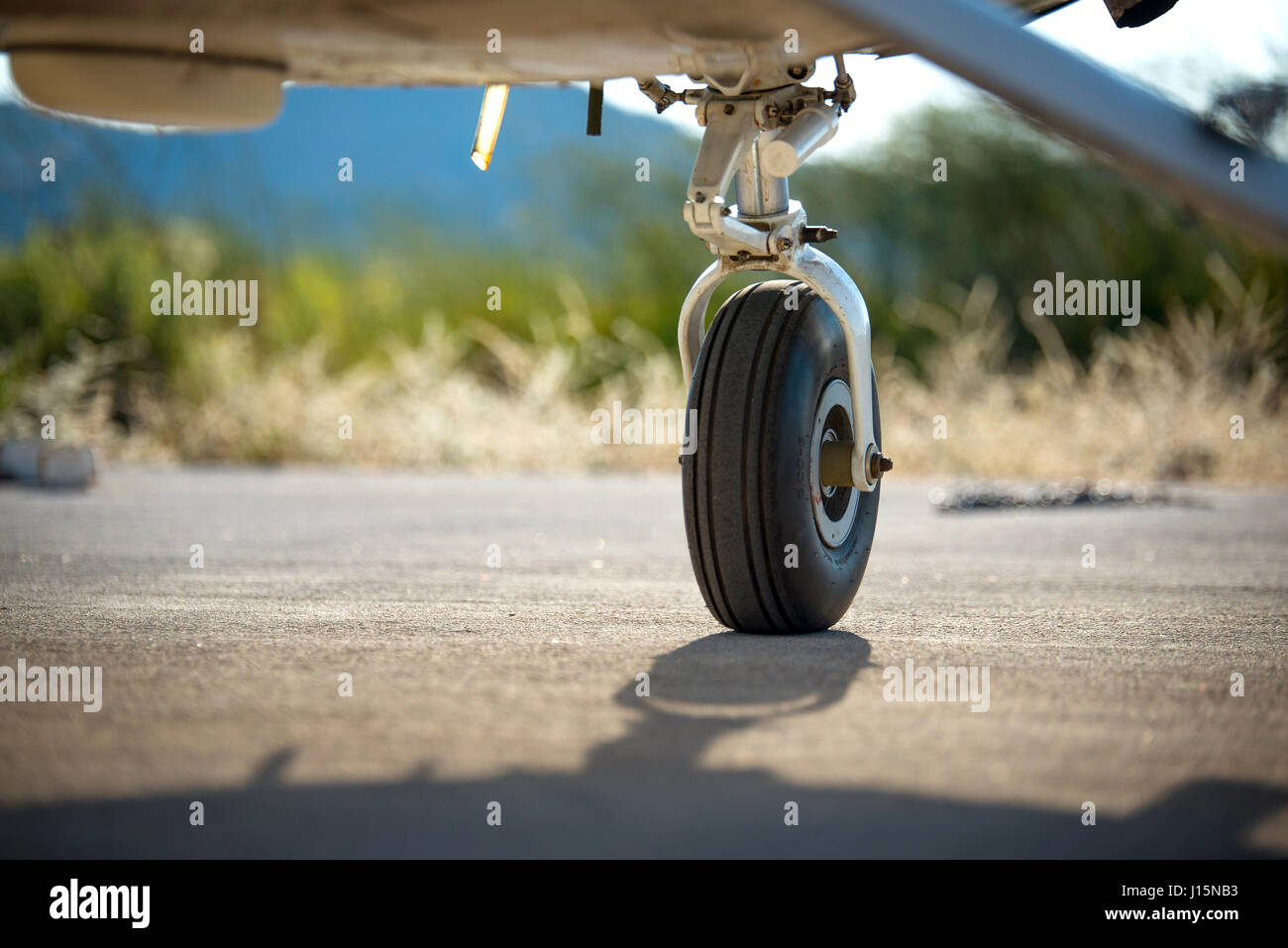 A rear landing gear and wheel chocks of a small aircraft on the ground ...