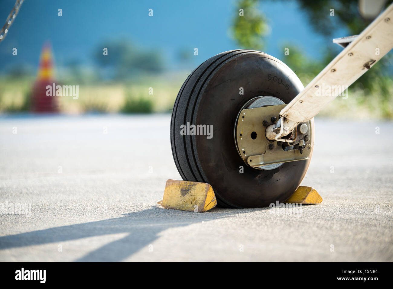 A rear landing gear and wheel chocks of a small aircraft on the ground ...
