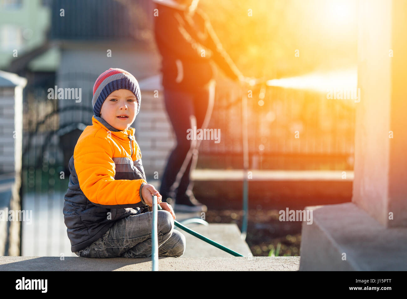 Little boy help mother with watering flowers, sunset Stock Photo - Alamy