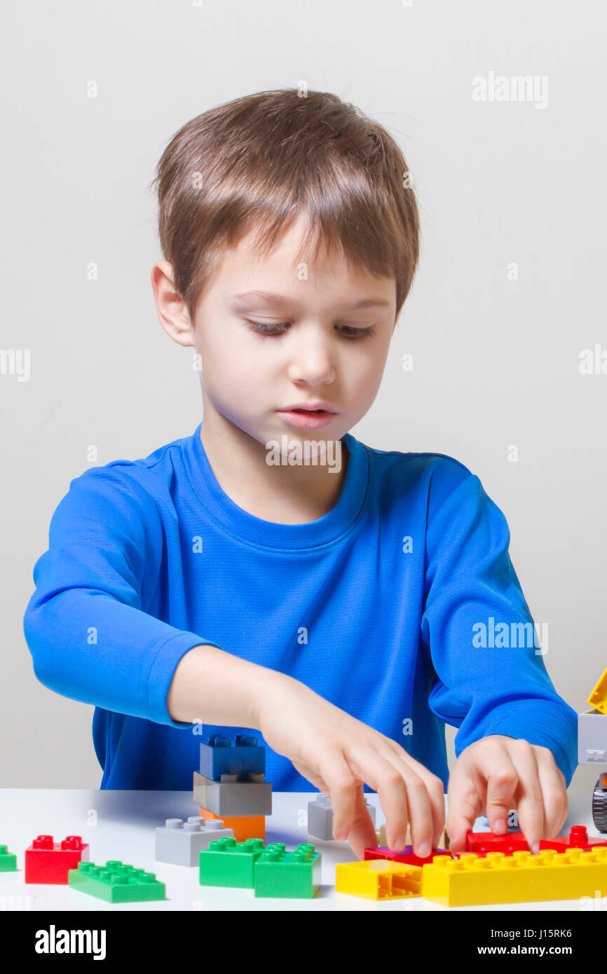 Little kid boy playing with colorful plastic construction bricks at ...
