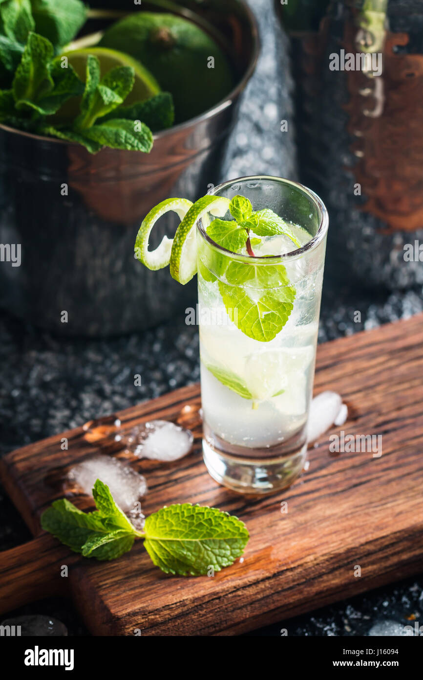cocktail with lime and mint in short glass on dark stone background ...
