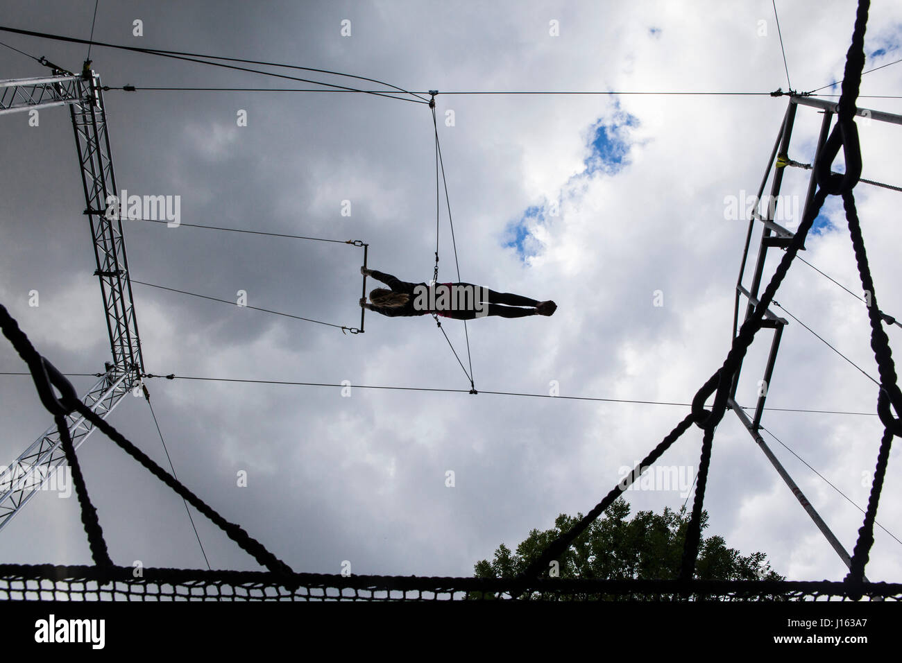 Trapeze studenst flying through the air. The Flying Trapeze School is ...