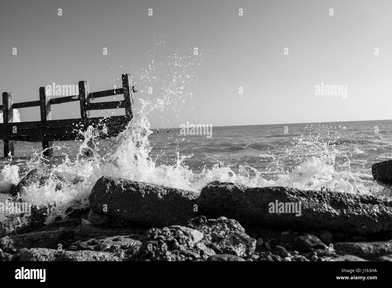 Splashing waves on rocks at beach b&w Stock Photo - Alamy