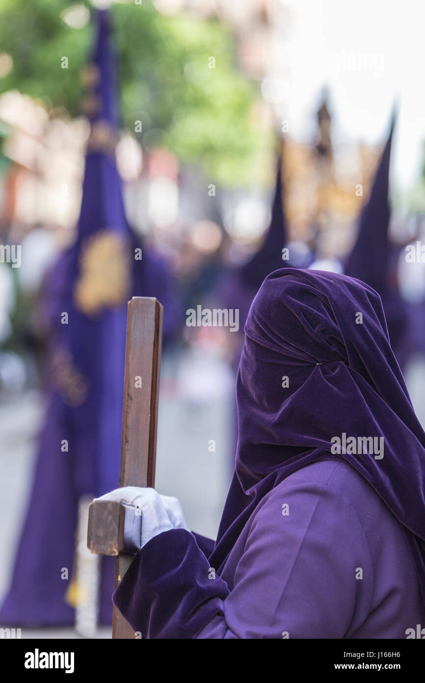 Penitent dressed in purple tunic of velvet resting on wooden cross ...