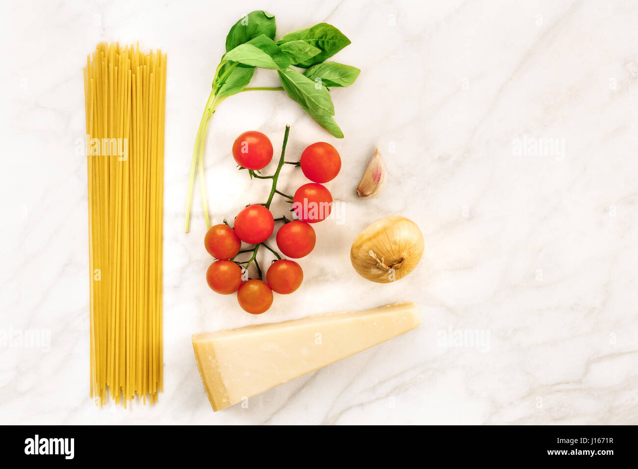 An overhead photo of basic pasta ingredients on a white marble table ...