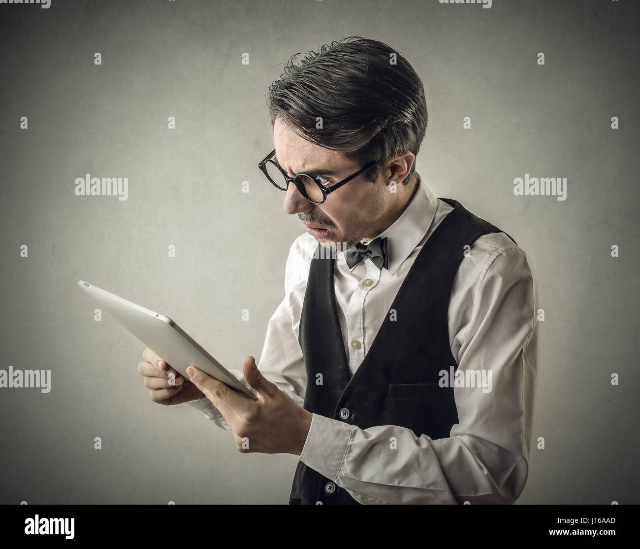 Confused man in glasses looking at tablet Stock Photo - Alamy