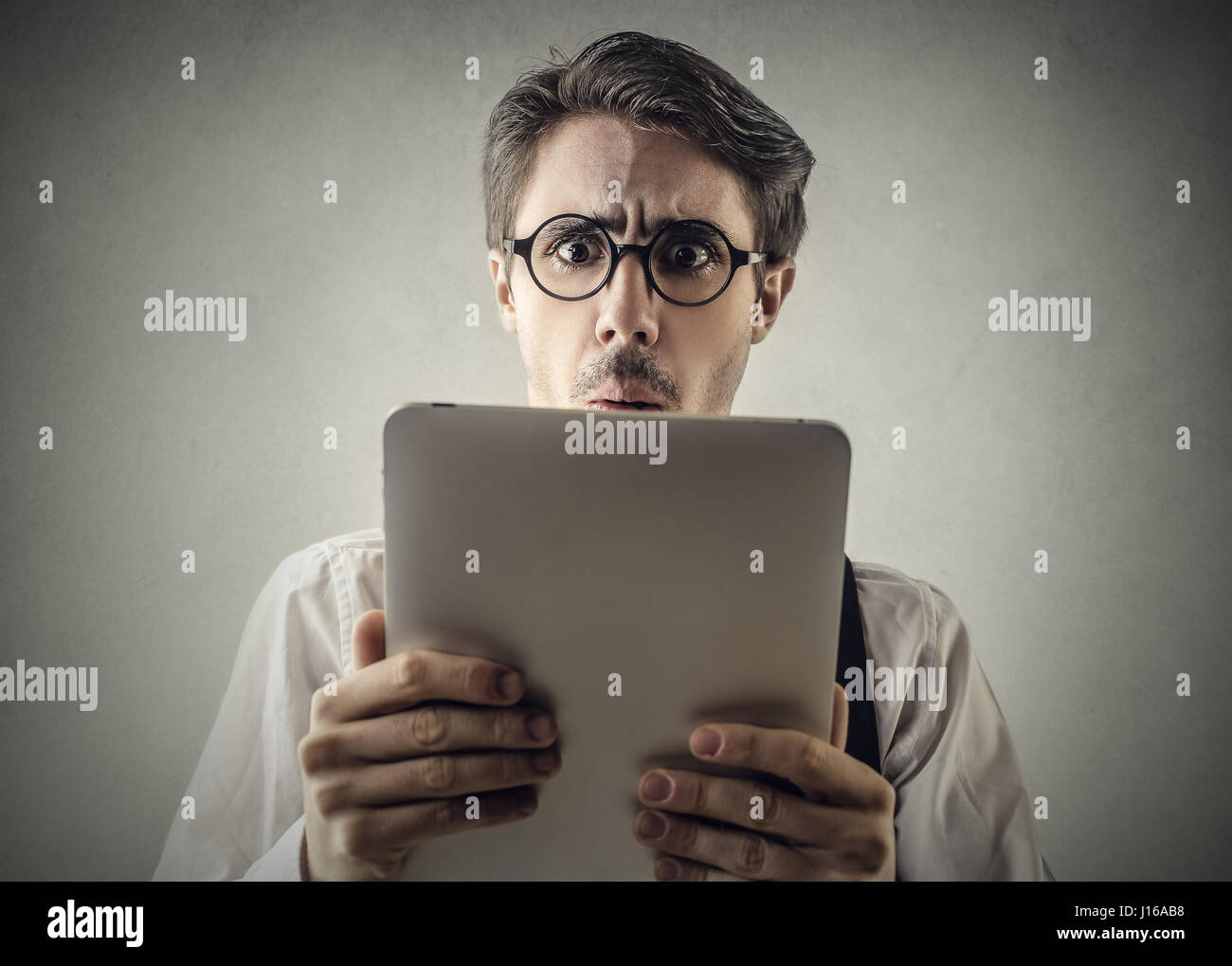 Confused man looking at tablet Stock Photo - Alamy
